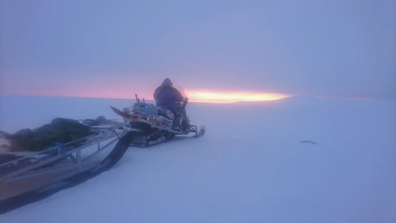 Snowmobile with sledge in snow storm