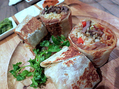 Beef burritos filled with refried beans, avocado & lettuce, eaten with ...