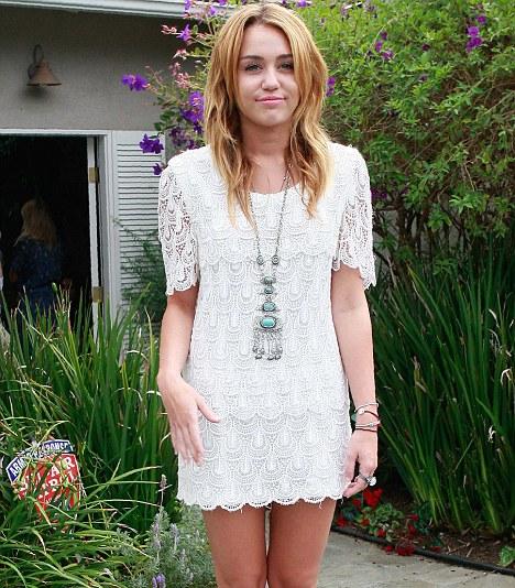 Miley Cyrus attempts a demure look in a pretty white lace dress... but ...