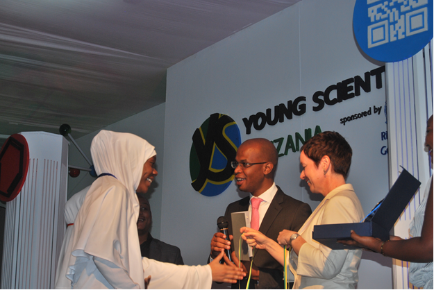 Hon January Makamba presents a prize to the over all winner of 2013 ...