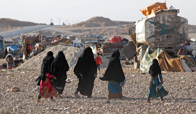 Displaced Syrian residents walk inside a refugee camp