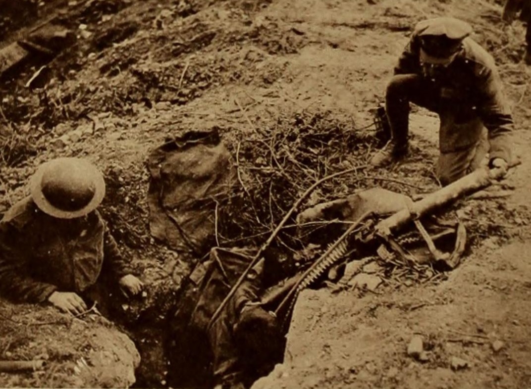 Two Allied soldiers examining the position of a dead German machine ...