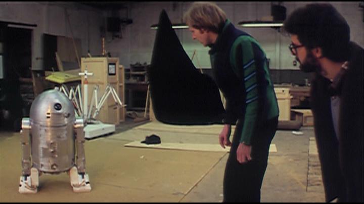 George Lucas watching as an early R2-D2 prop comes to life.